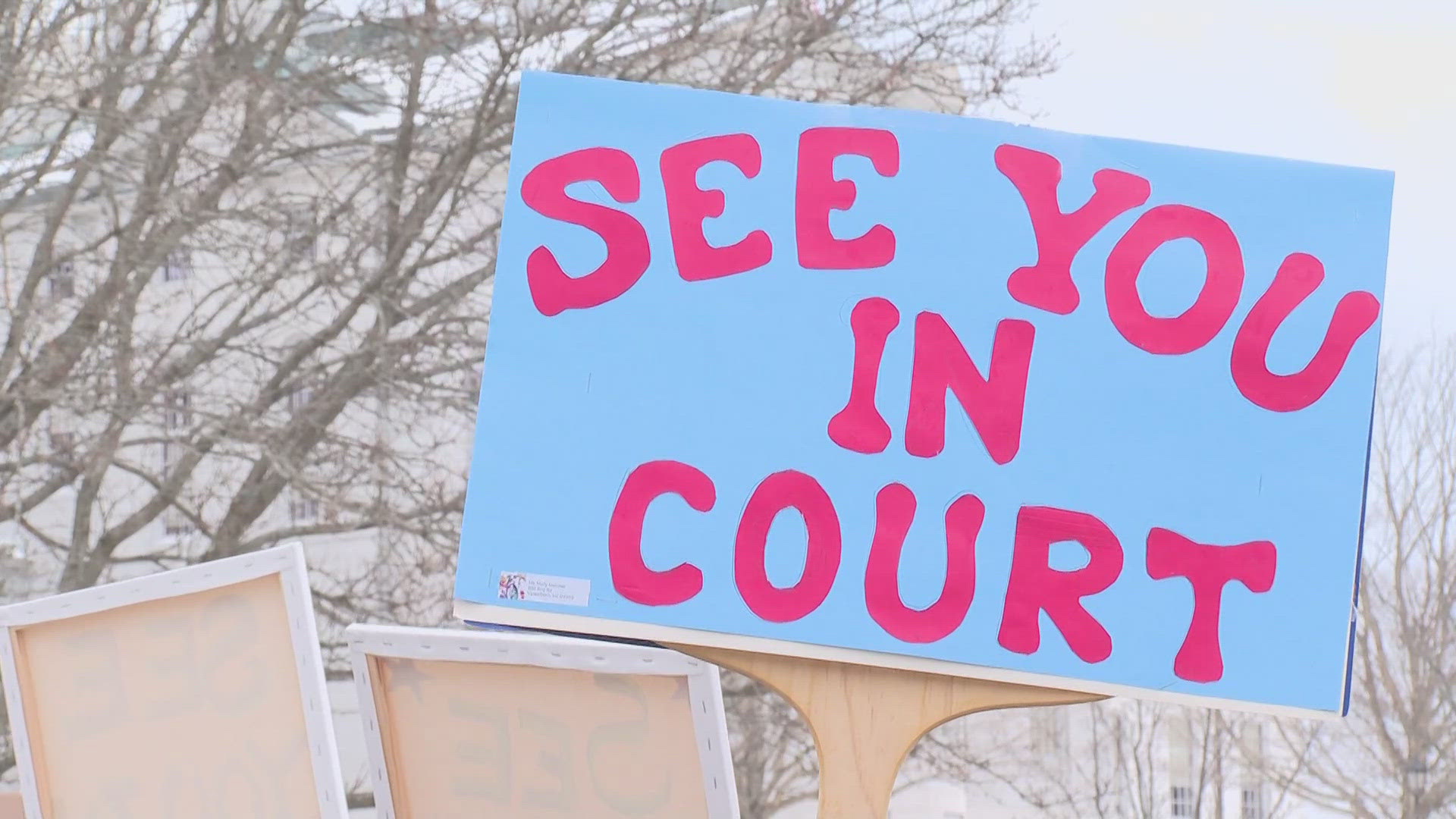 Protesters rally after Mills clashes with Trump over transgender ...